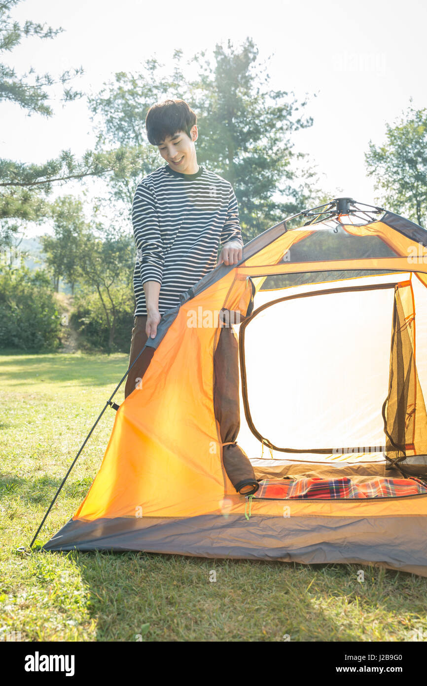Young smiling man setting up tent Stock Photo - Alamy