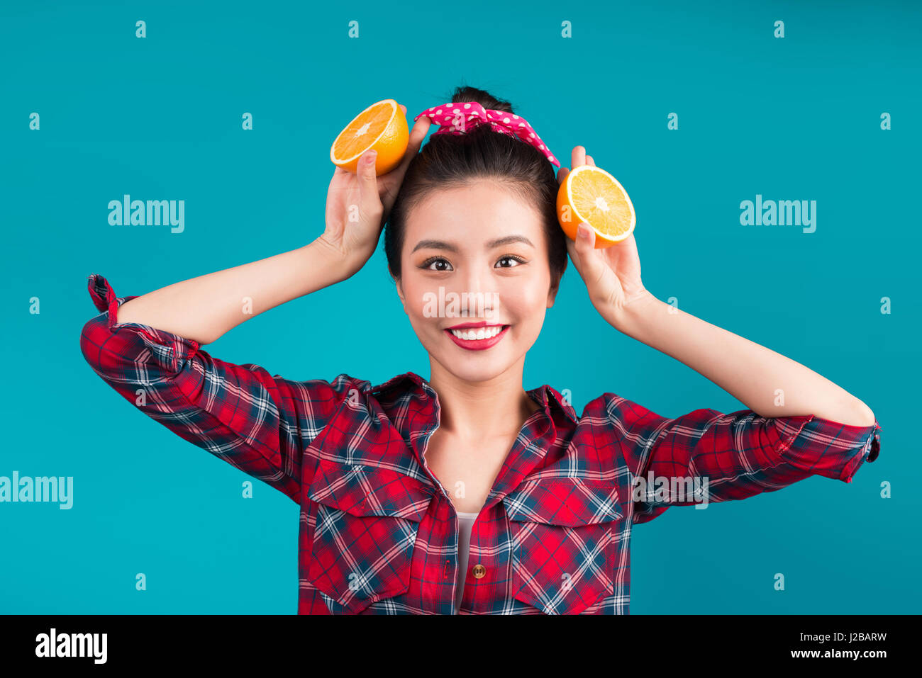 Healthy food. Smiling lovely pinup asian girl holding orange over blue ...