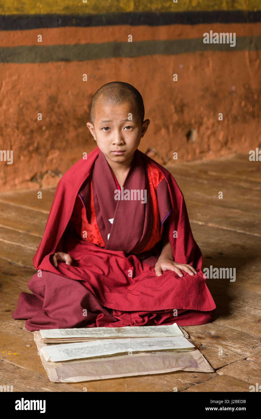 Bhutan, Paro. A young monk pausing in his study of the Sanskrit, inside ...
