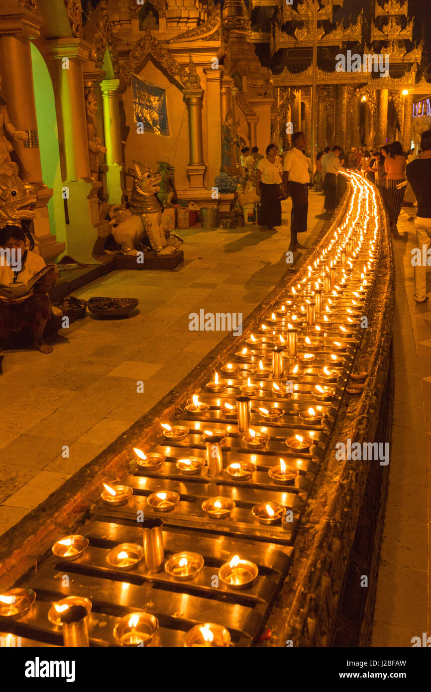 Myanmar, Yangon. A long curving line of oil lamps in Shwedagon Pagoda ...