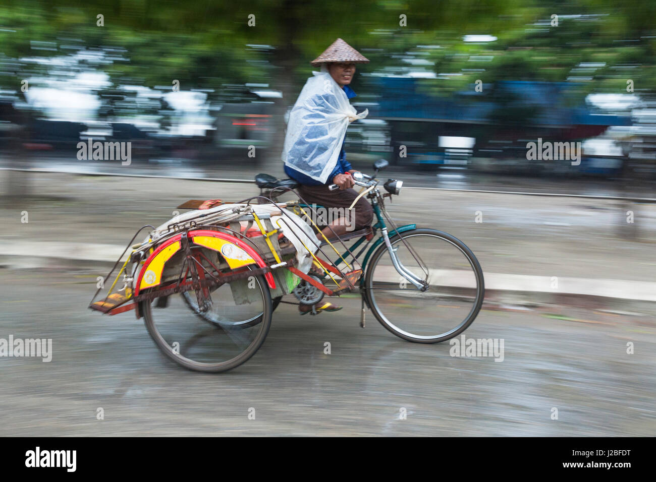 Myanmar, Mandalay. Man zooms by on bicycle in the rain Stock Photo - Alamy