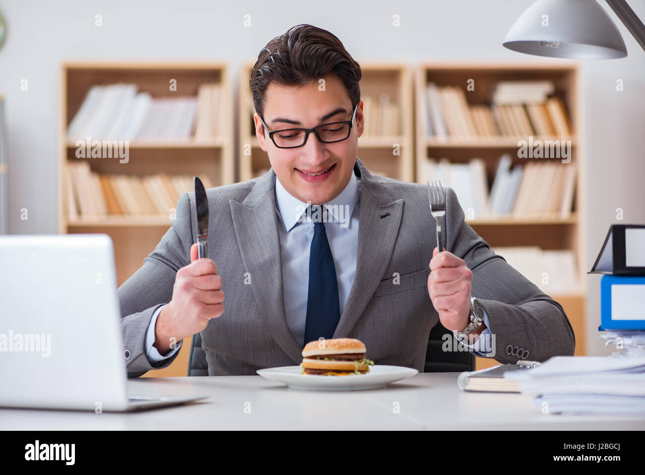 Hungry funny businessman eating junk food sandwich Stock Photo - Alamy