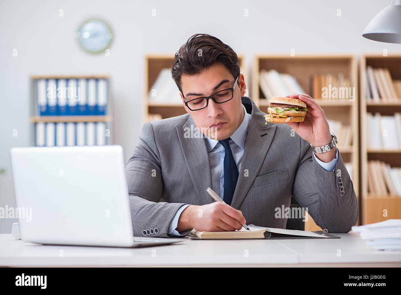 Hungry funny businessman eating junk food sandwich Stock Photo - Alamy
