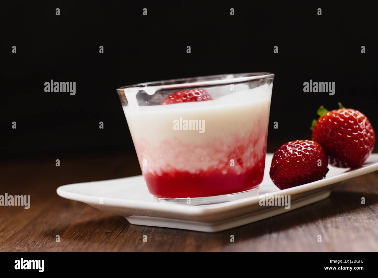 Strawberry flavored tapioca pudding in glass cup on dark wood table and ...