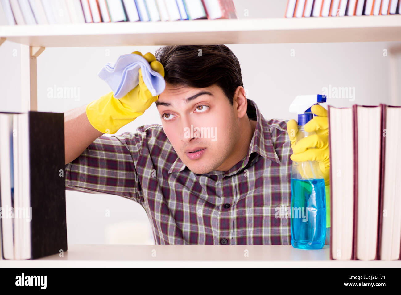 Man cleaning dust from bookshelf Stock Photo - Alamy