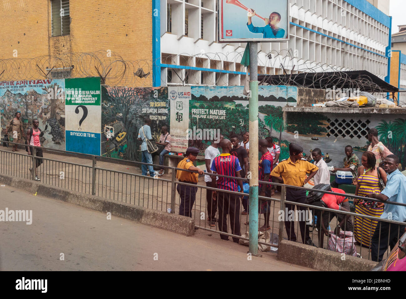 Africa, Sierra Leone, Freetown. People queueing near a USAID and forest ...