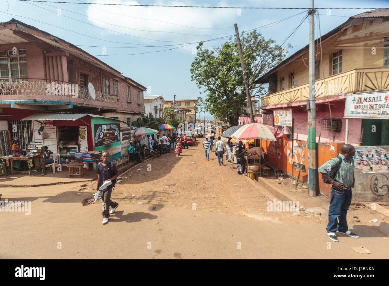 Africa, Sierra Leone, Freetown. People and storefronts at a dusty ...