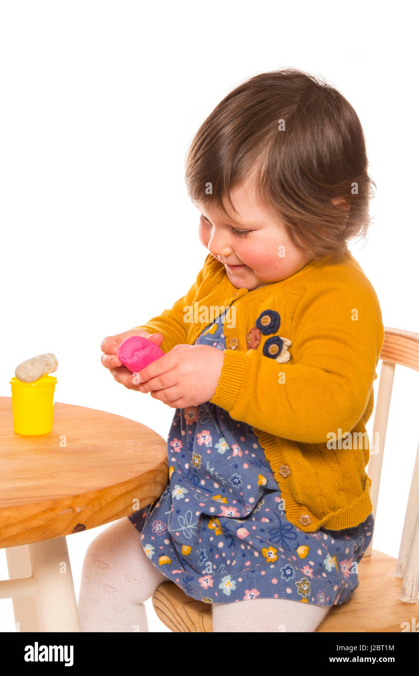 toddler sitting at a table playing with playdough cutout Stock Photo ...