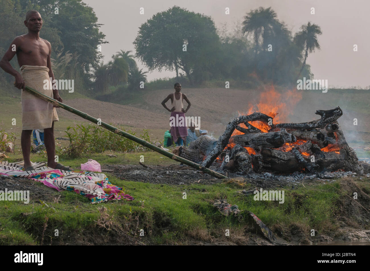 India, Ganges River, village men performing a traditional cremation on ...