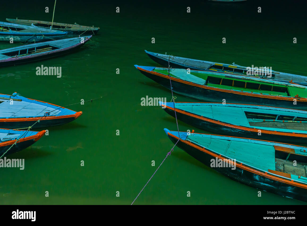 India, Varanasi 9 blue, red and green rowboats on the green water of ...
