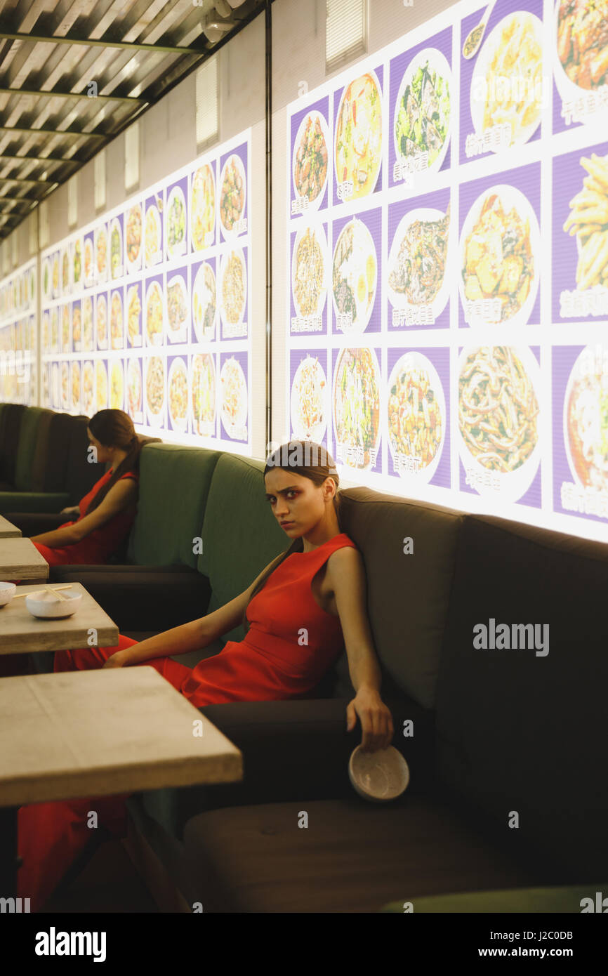 Side view of serious woman in red suit which lying on armchair in ...