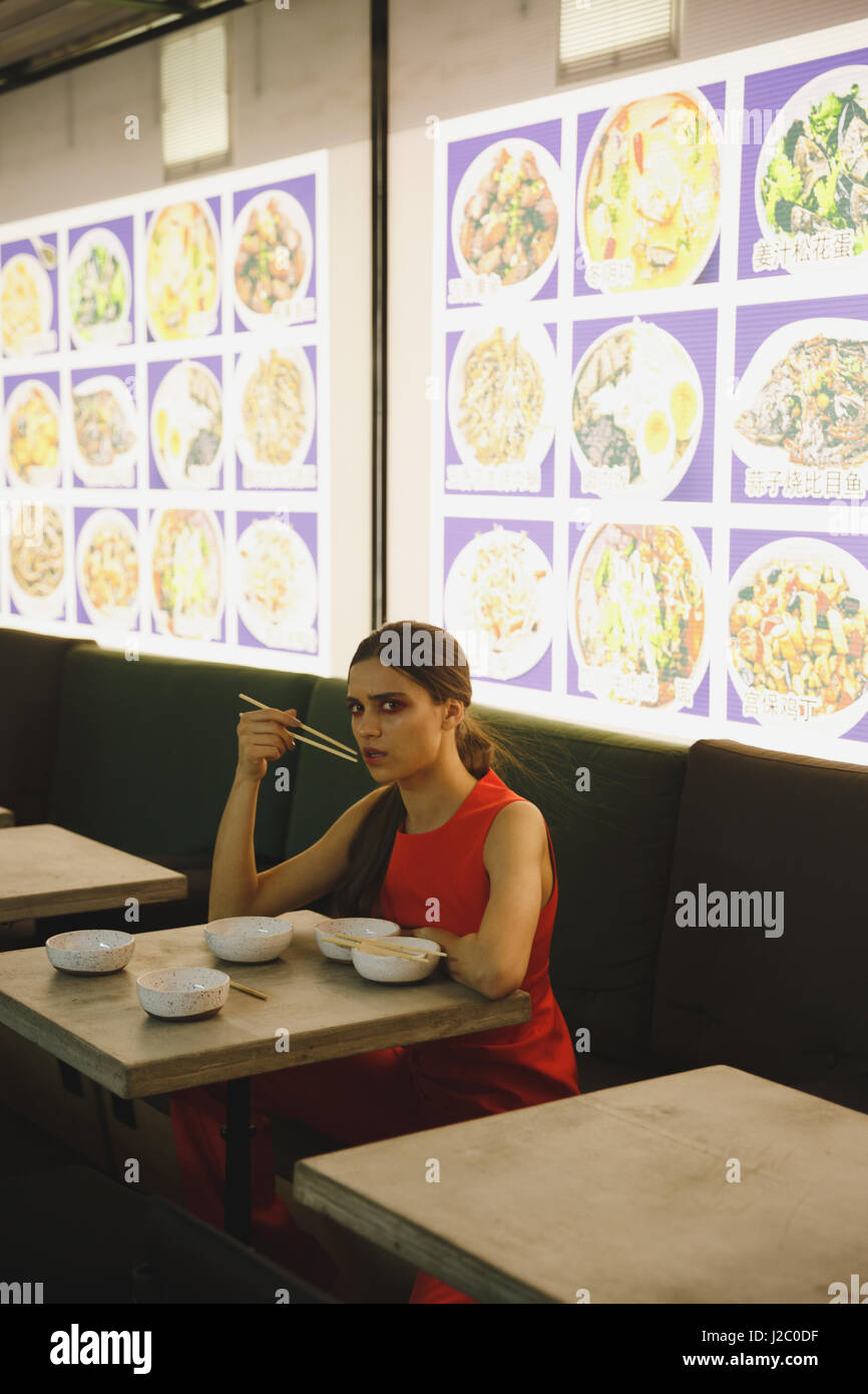 Side view of woman in suit which eating by the table. Vertical image ...