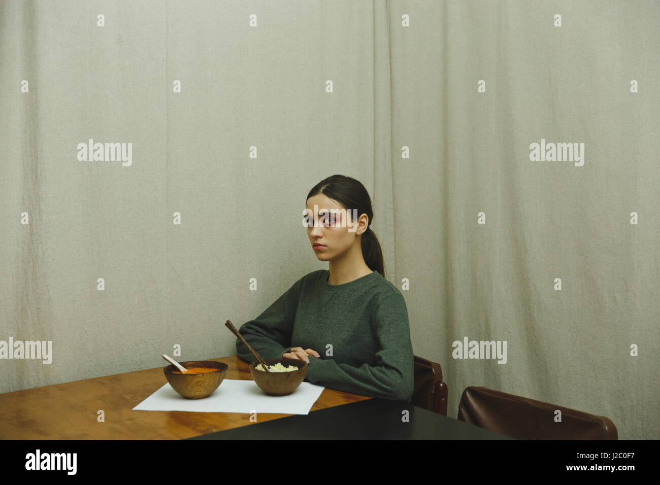 Side view of a calm woman in sweater eating by the table in eatery ...