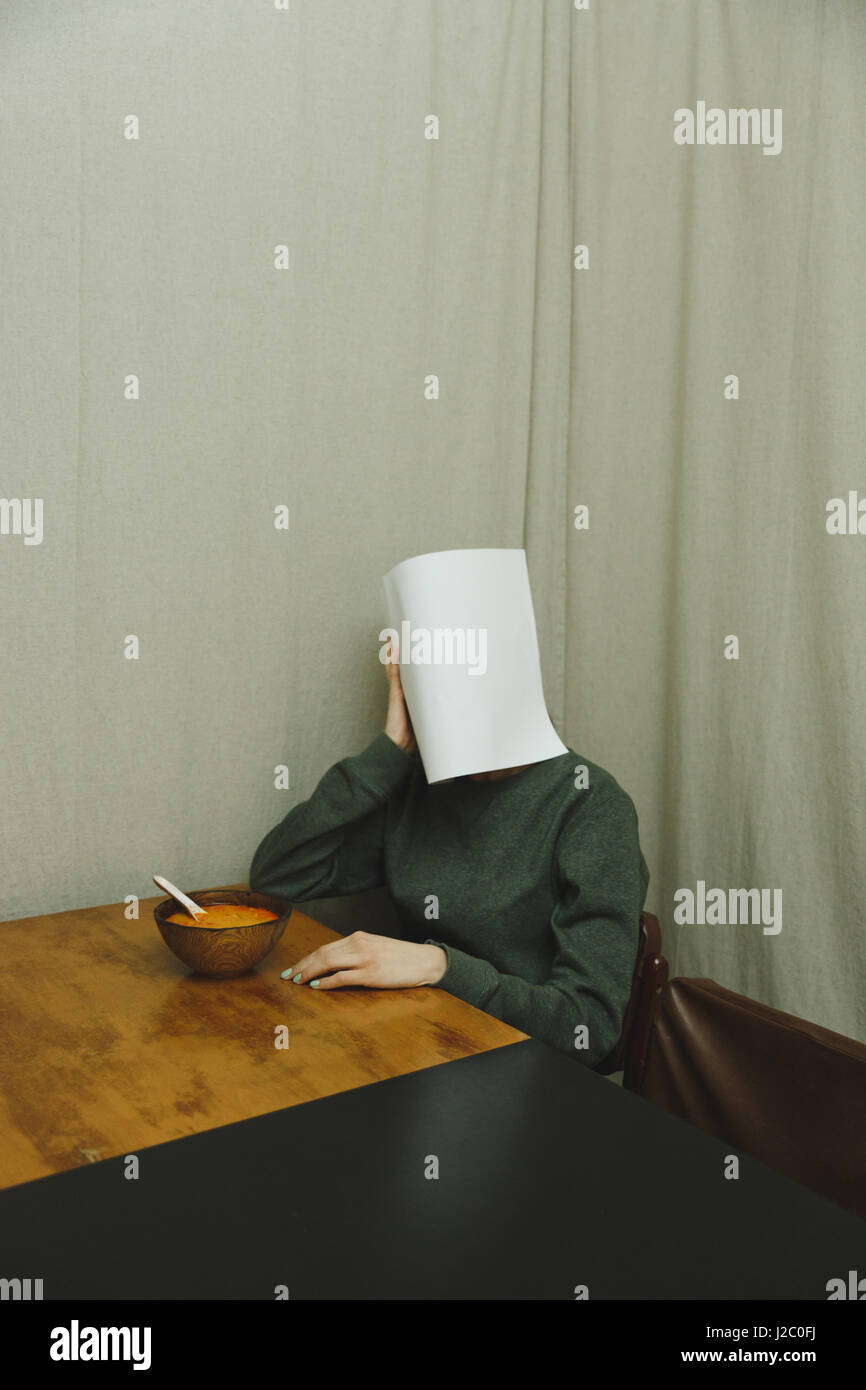 Vertical image of a woman hiding behind the piece of paper while ...