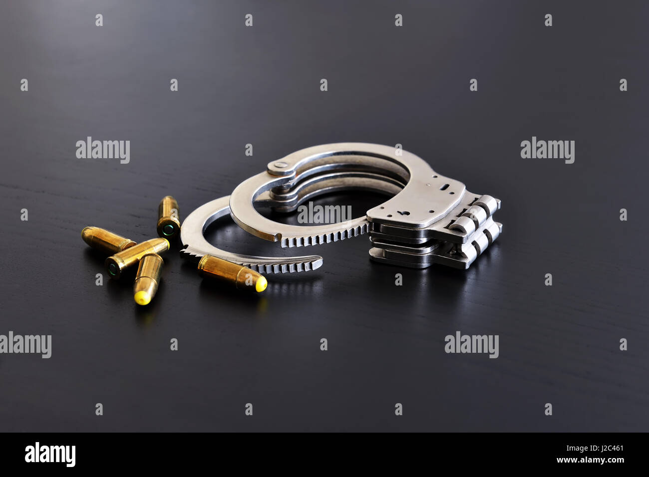 Police handcuffs and pistol bullets on dark table Stock Photo - Alamy