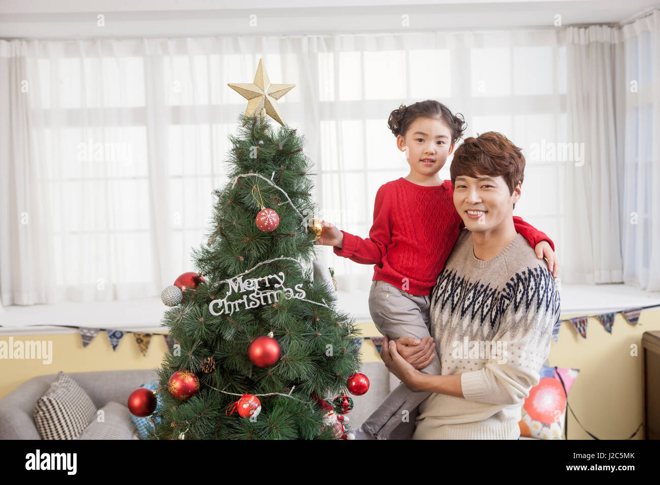 Smiling father and daughter with Christmas tree Stock Photo - Alamy
