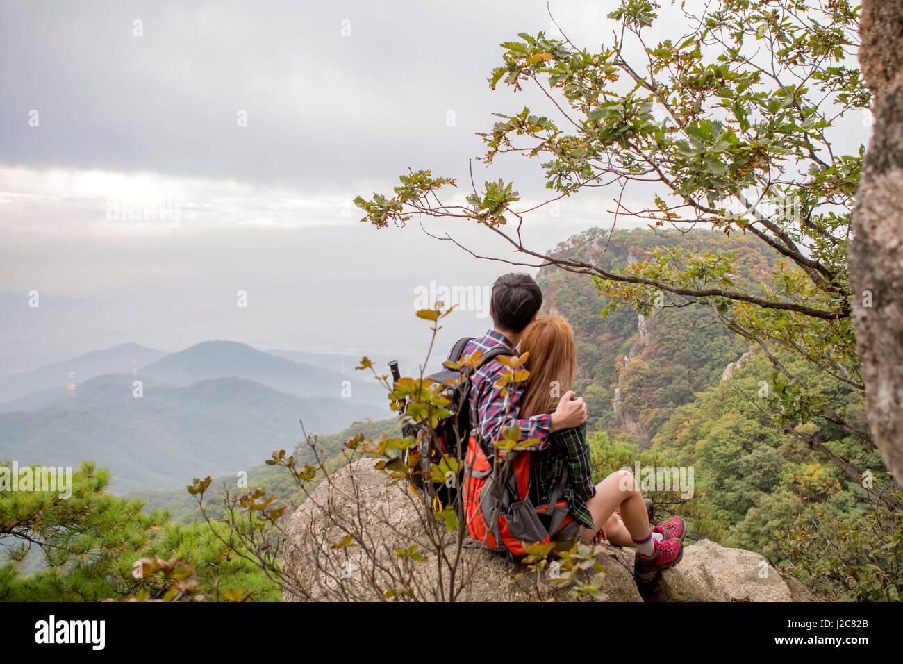 Back of couple trekkers sitting and hugging on a rock Stock Photo - Alamy