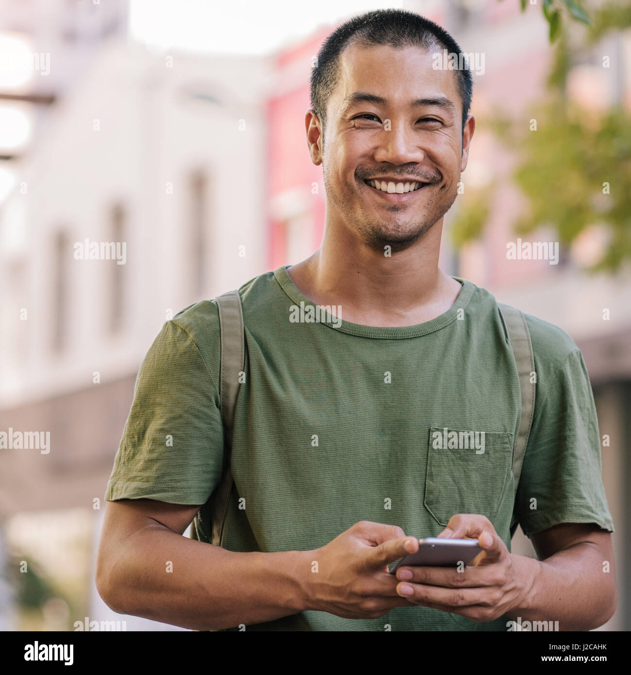 Happy Asian man sending a text on his cellphone outside Stock Photo - Alamy