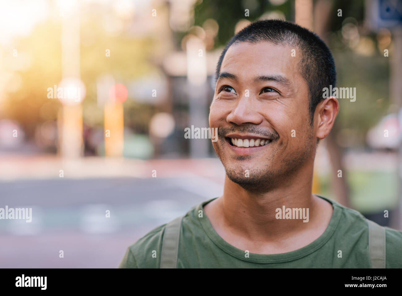 Handsome young Asian man standing on a city street smiling Stock Photo ...