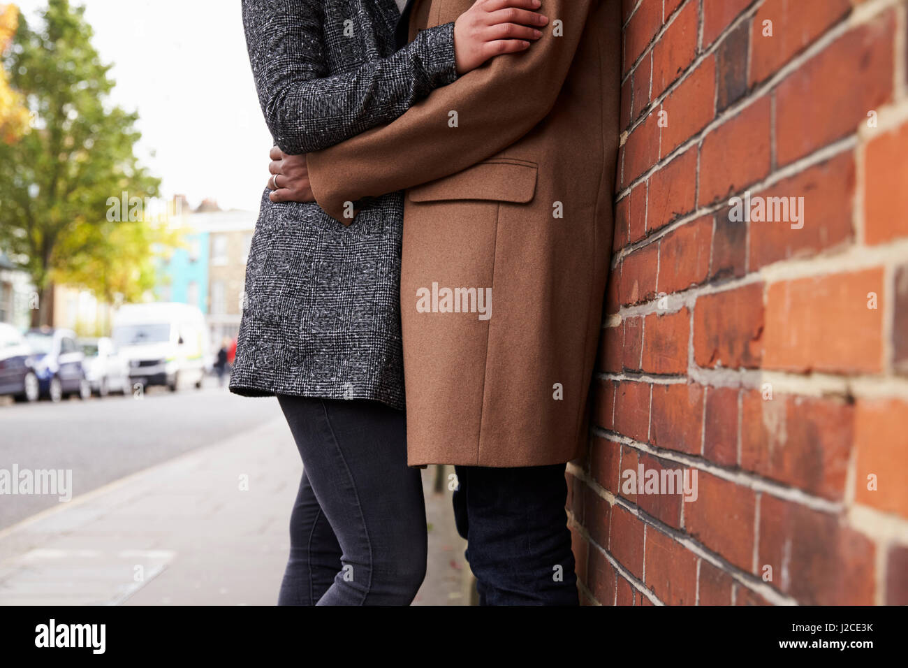 Close Up Of Couple Standing By Wall On Street And Hugging Stock Photo ...