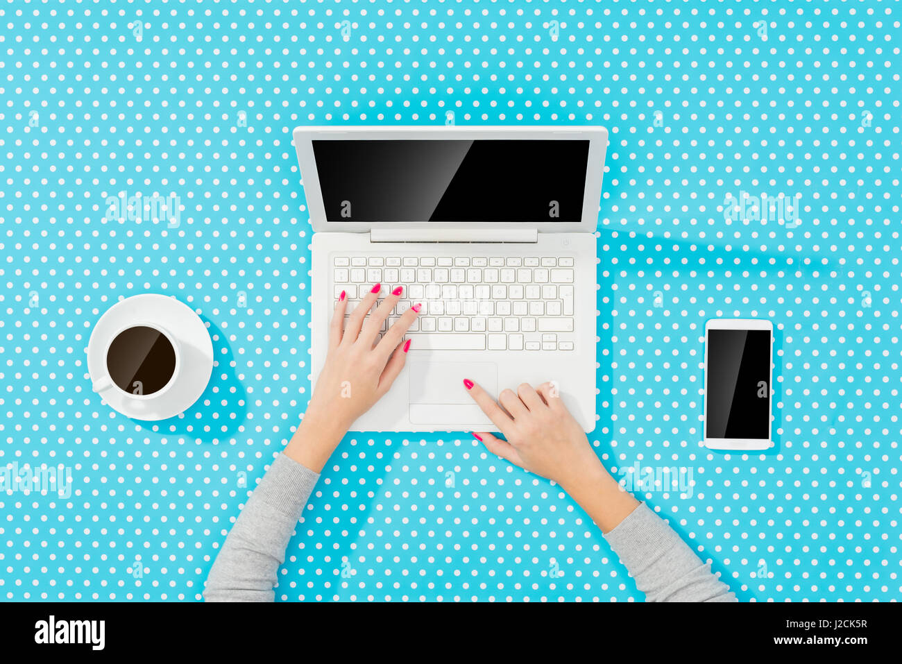 Woman using modern laptop over blue dotted table Stock Photo - Alamy