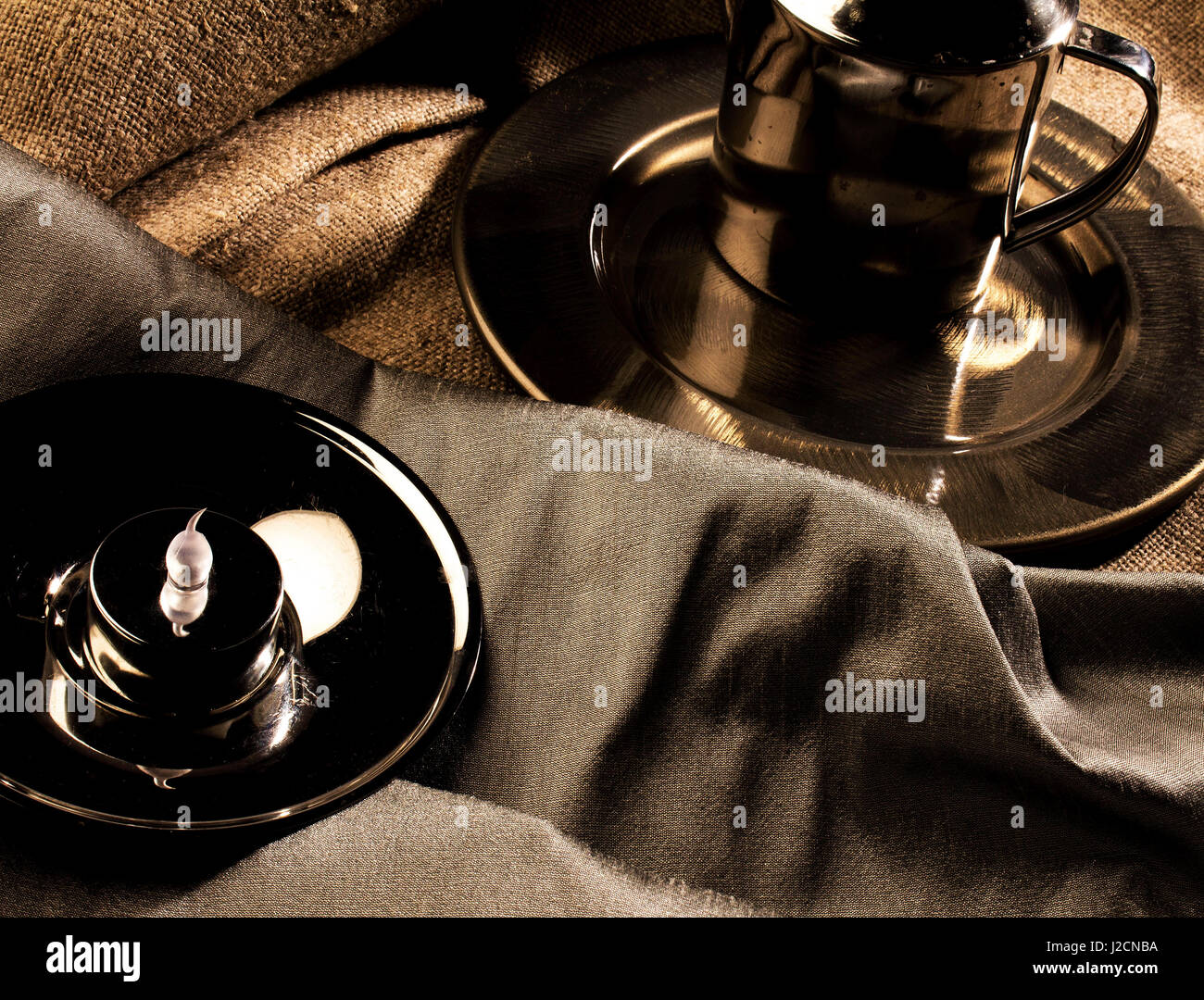 A bronze, gold and silver still life set up, containing metal plates, a ...