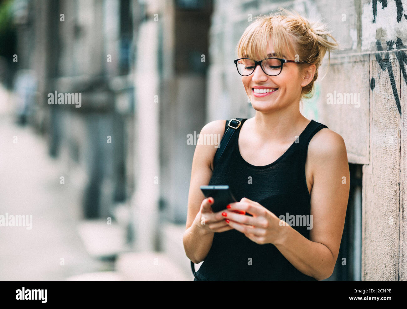 Smiling beautiful urban woman texting on the smart phone. Toned photo ...