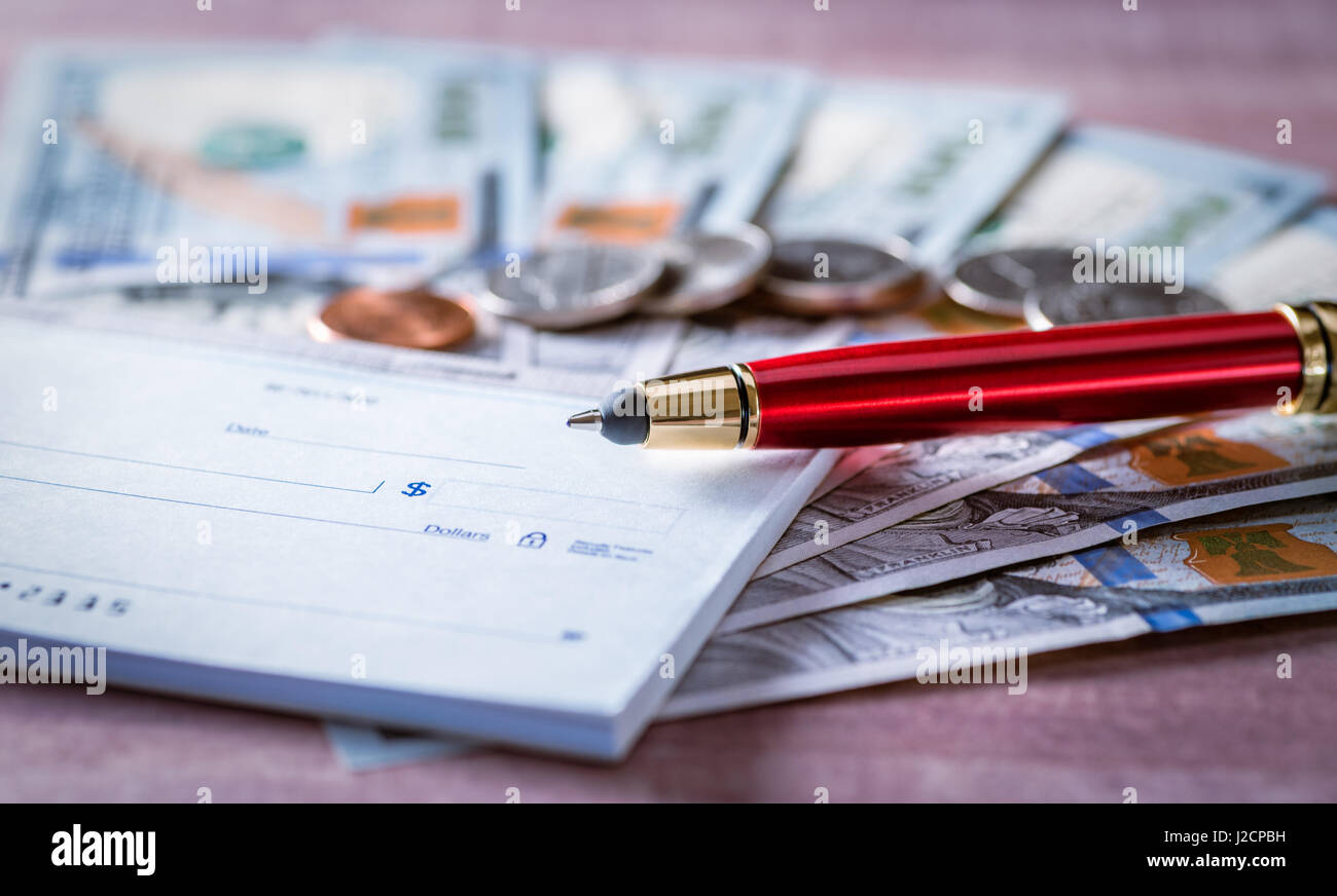 Financial concept. Check book, red pen, 100 dollar bills, coins ...