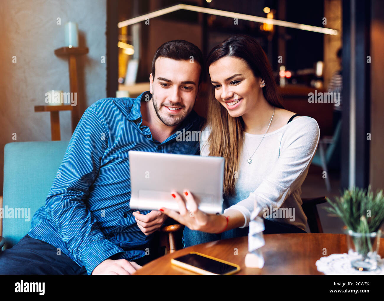 Happy young couple browsing the internet at the tablet Stock Photo - Alamy