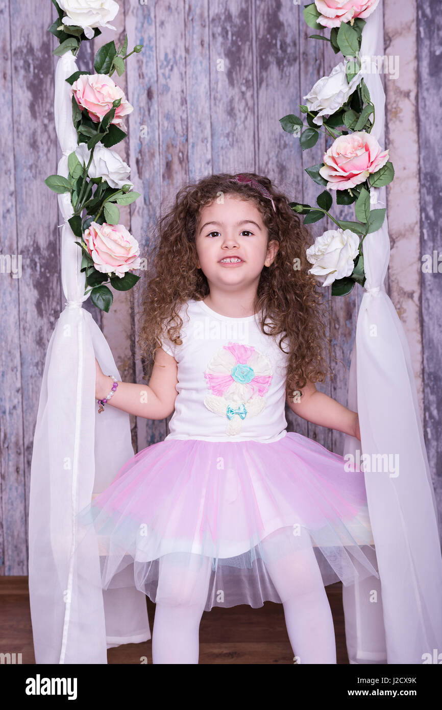 Cute little girl swinging on a cradle with flowers Stock Photo - Alamy