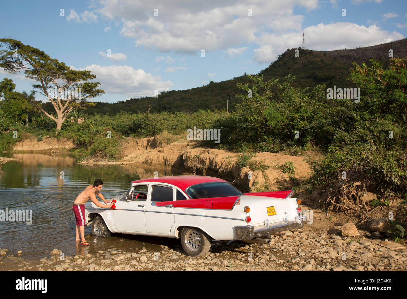 Cuba, Trinidad, young man washing classic car in river. (Editorial Use ...