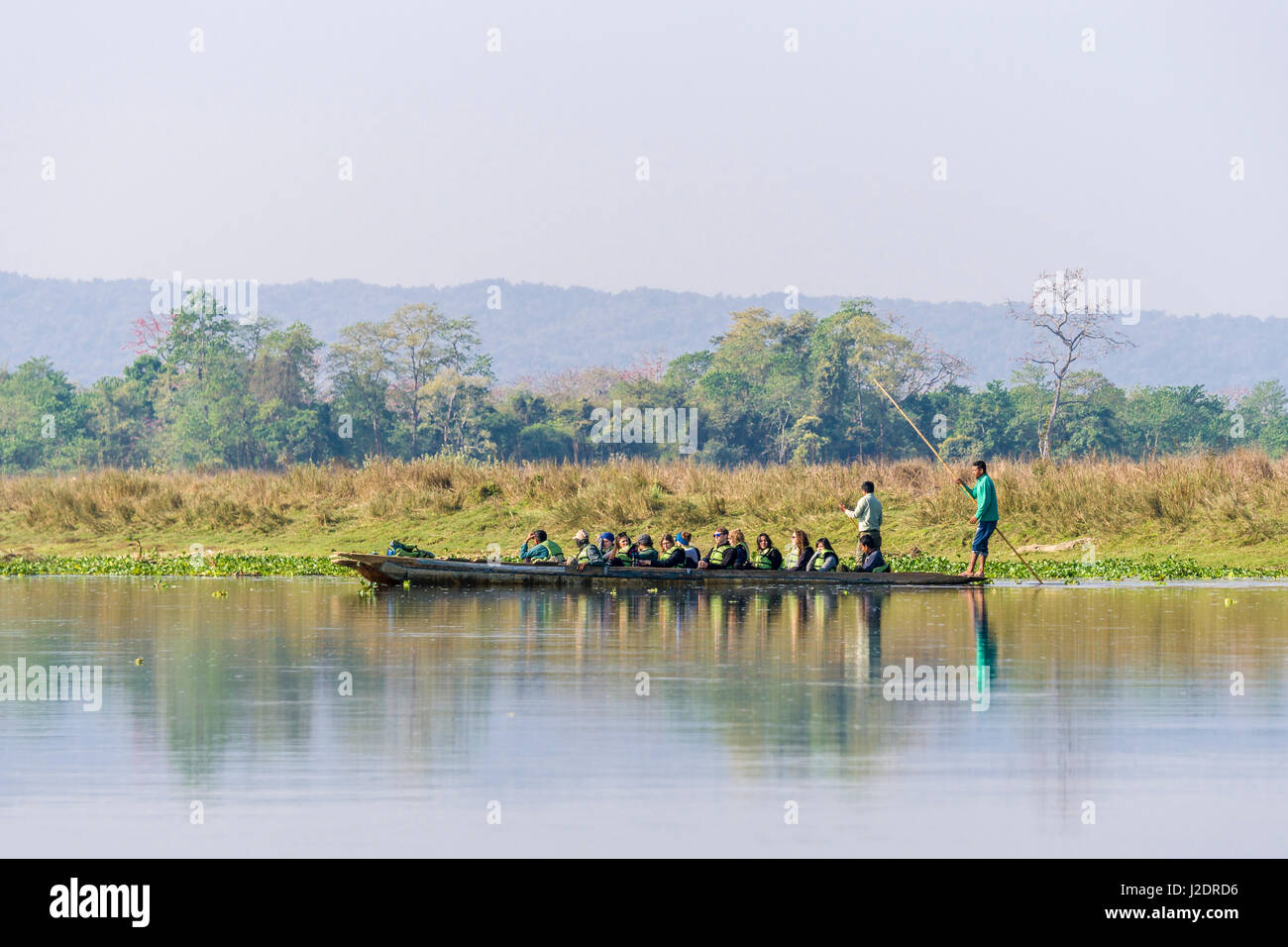 A boat with tourists is floating on the Rapti River in Chitwan National ...