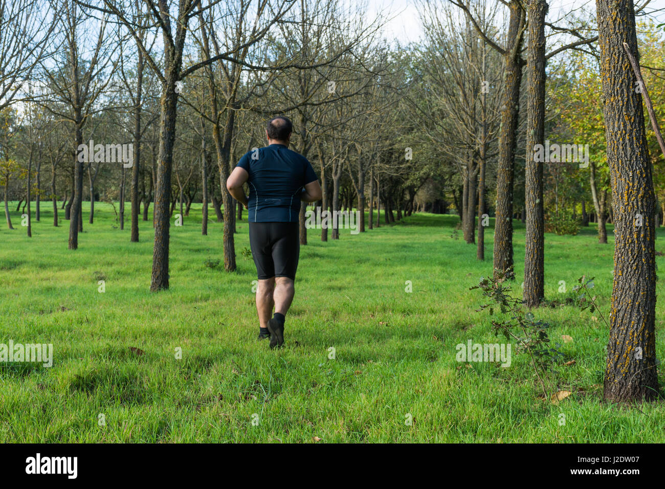 Big belly man jogging , exercising, doing cardio in the park , slightly ...