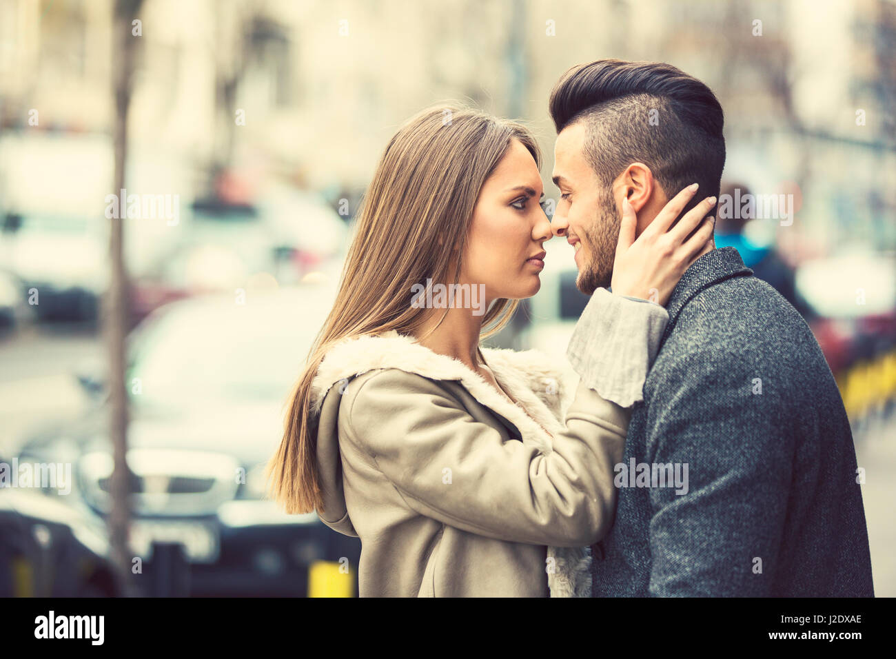 Portrait of beautiful smiling young couple outside, side view face to ...