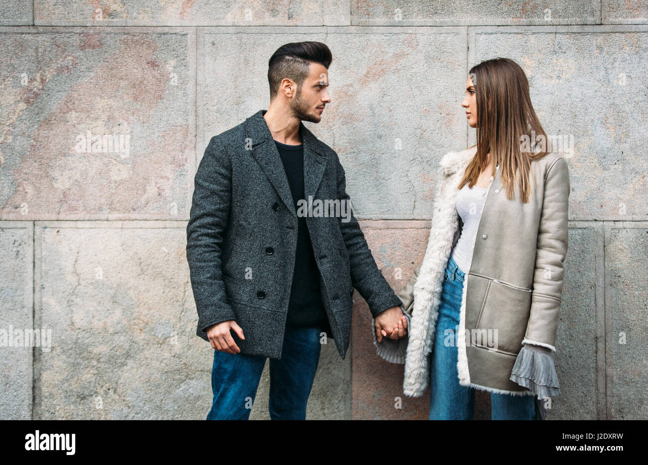 Portrait of couple standing against wall, relationship concept. Added ...