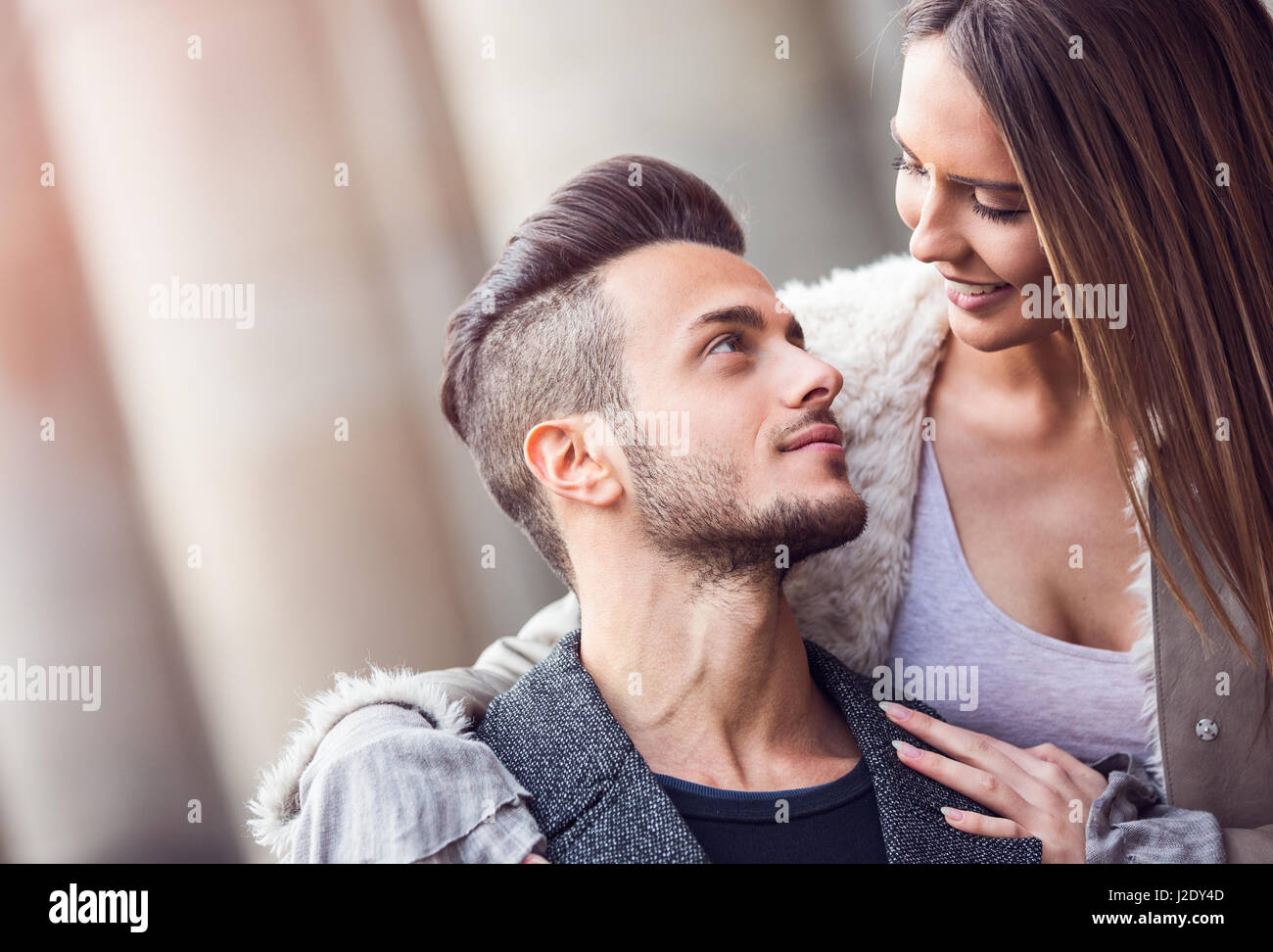 Portrait of beautiful smiling young couple outside, side view face to ...