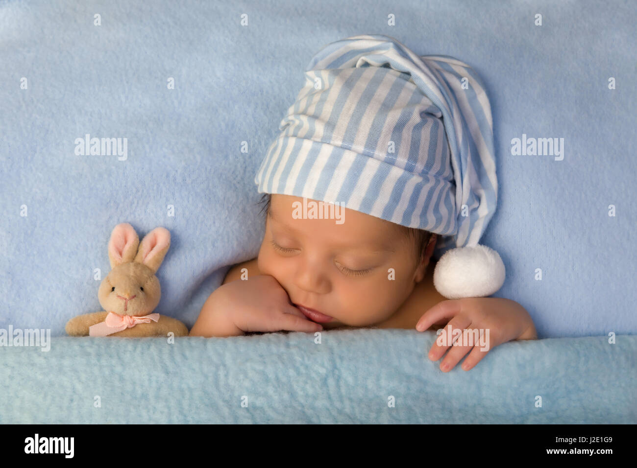 African mixed race baby of 7 days old sleeping in a light blue bed ...