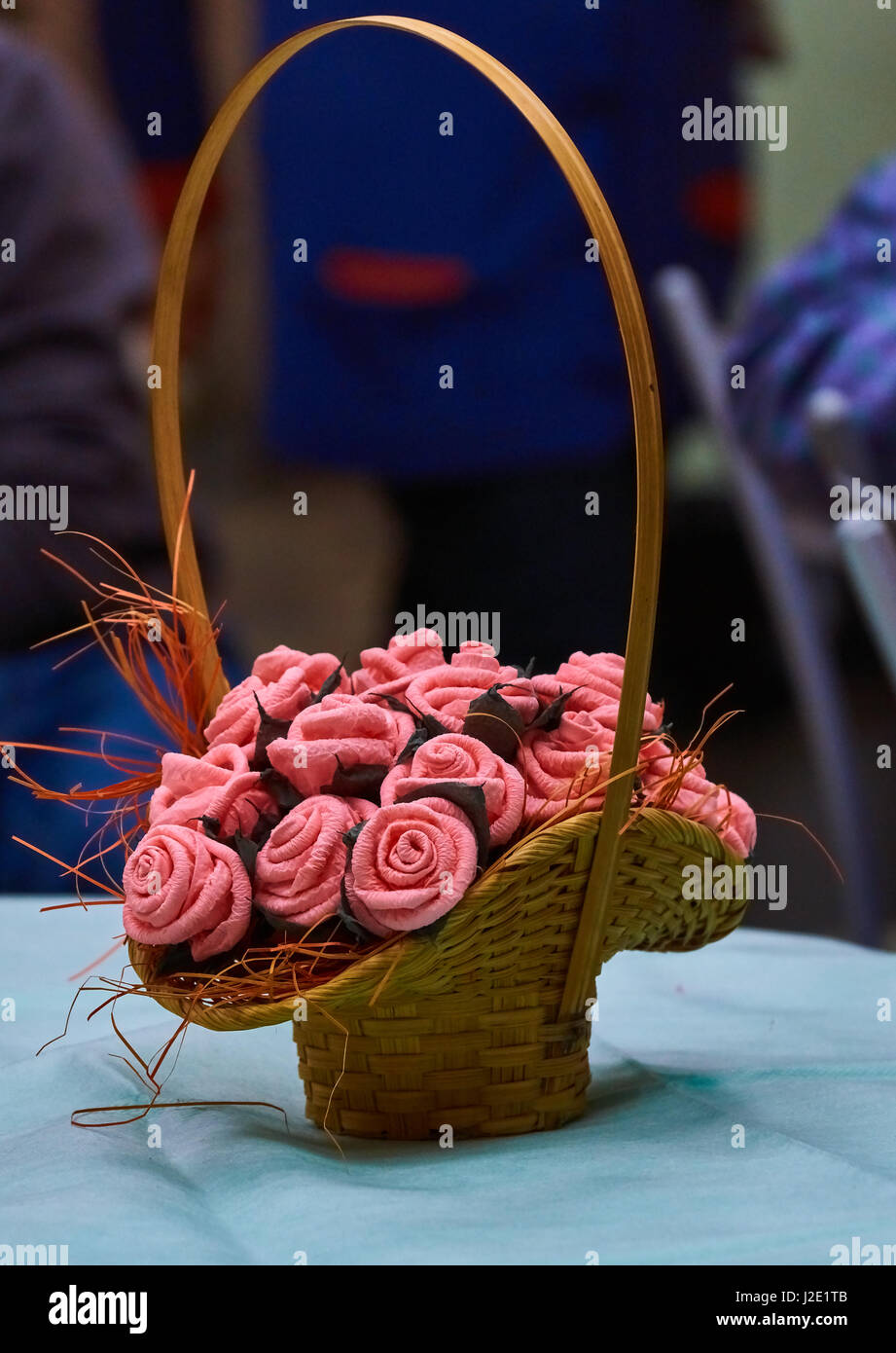 Composition "Tea roses in a woven straw basket".On the table stands a ...