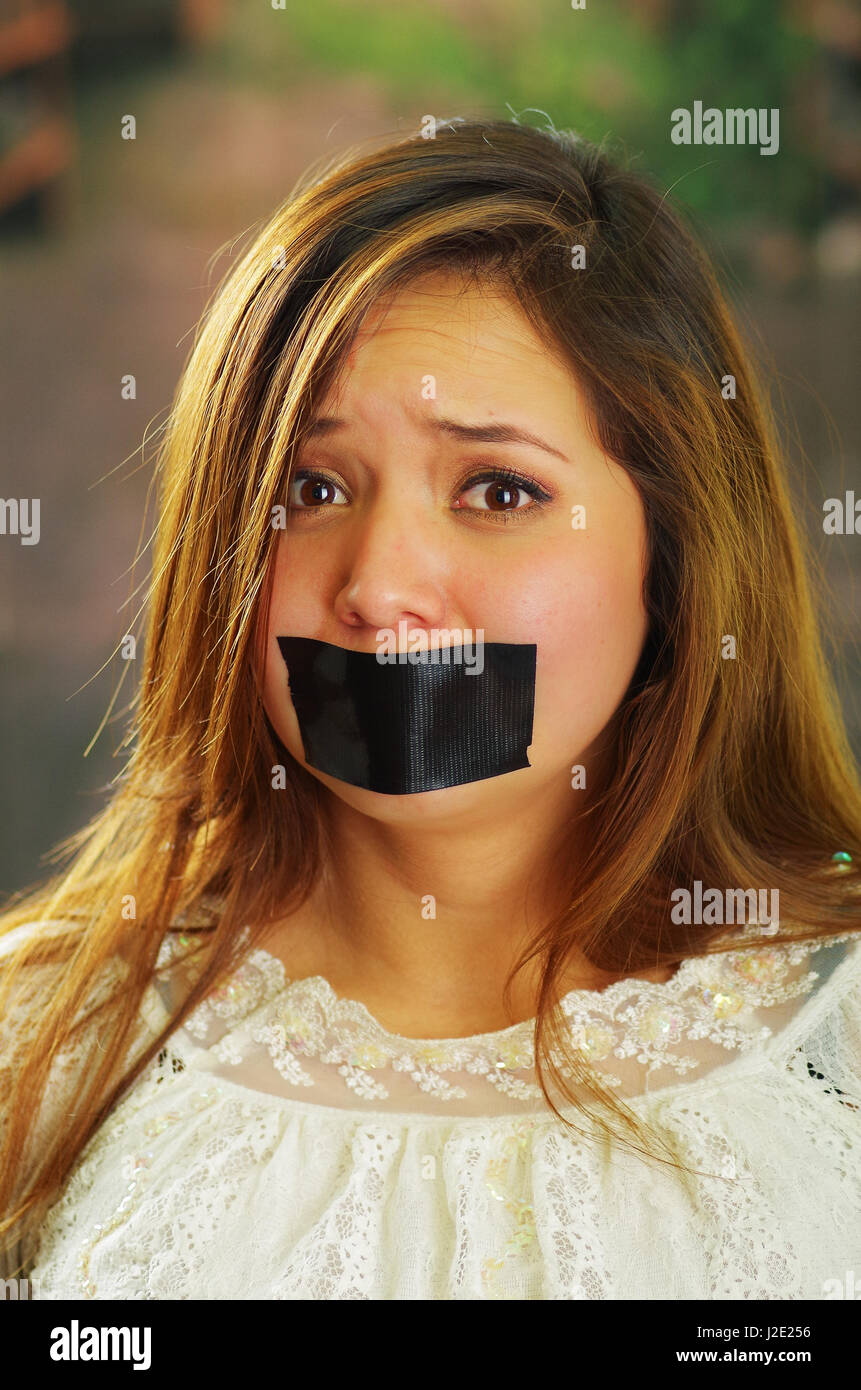 Scared beautiful young woman being silenced with tape on her mouth ...