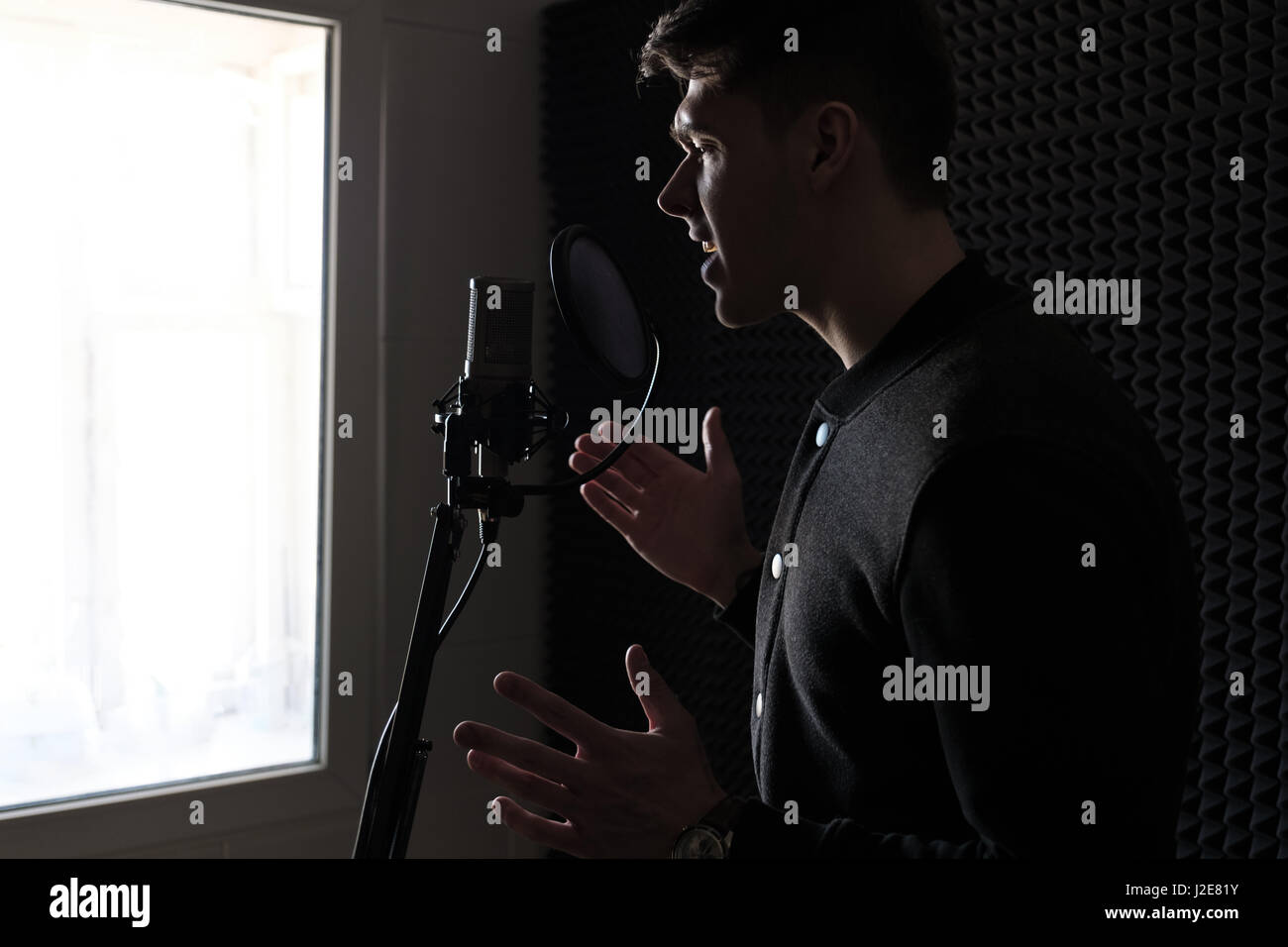 The guy sings in front of the microphone on the stand standing in ...