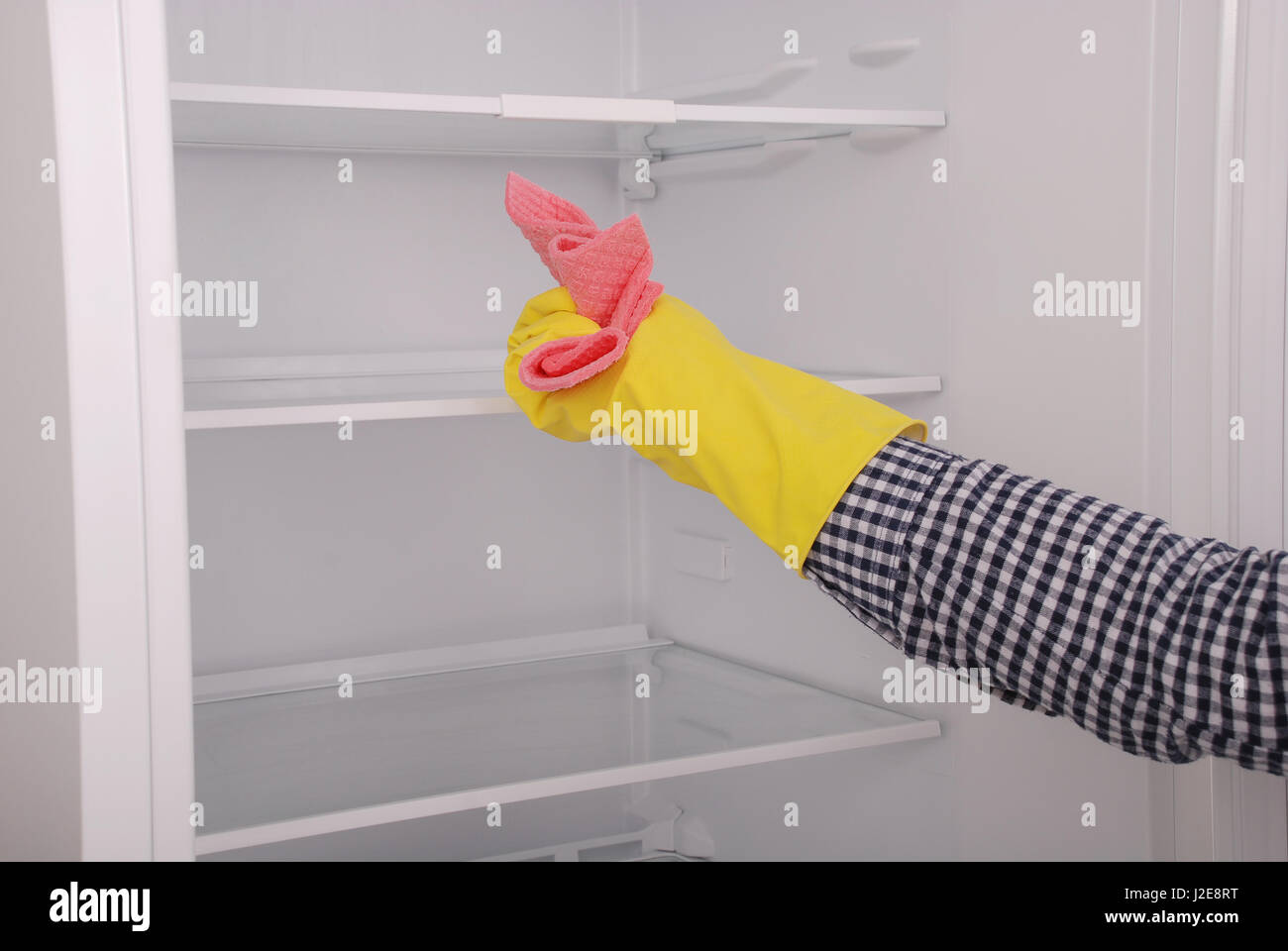 Young girl cleaning empty fridge with a sponge. Beautiful young girl ...