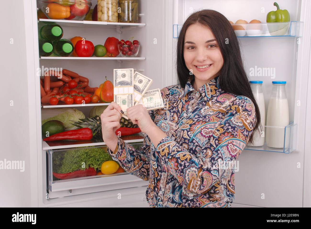 Young girl holding dollars on the refrigerator background. Beautiful ...