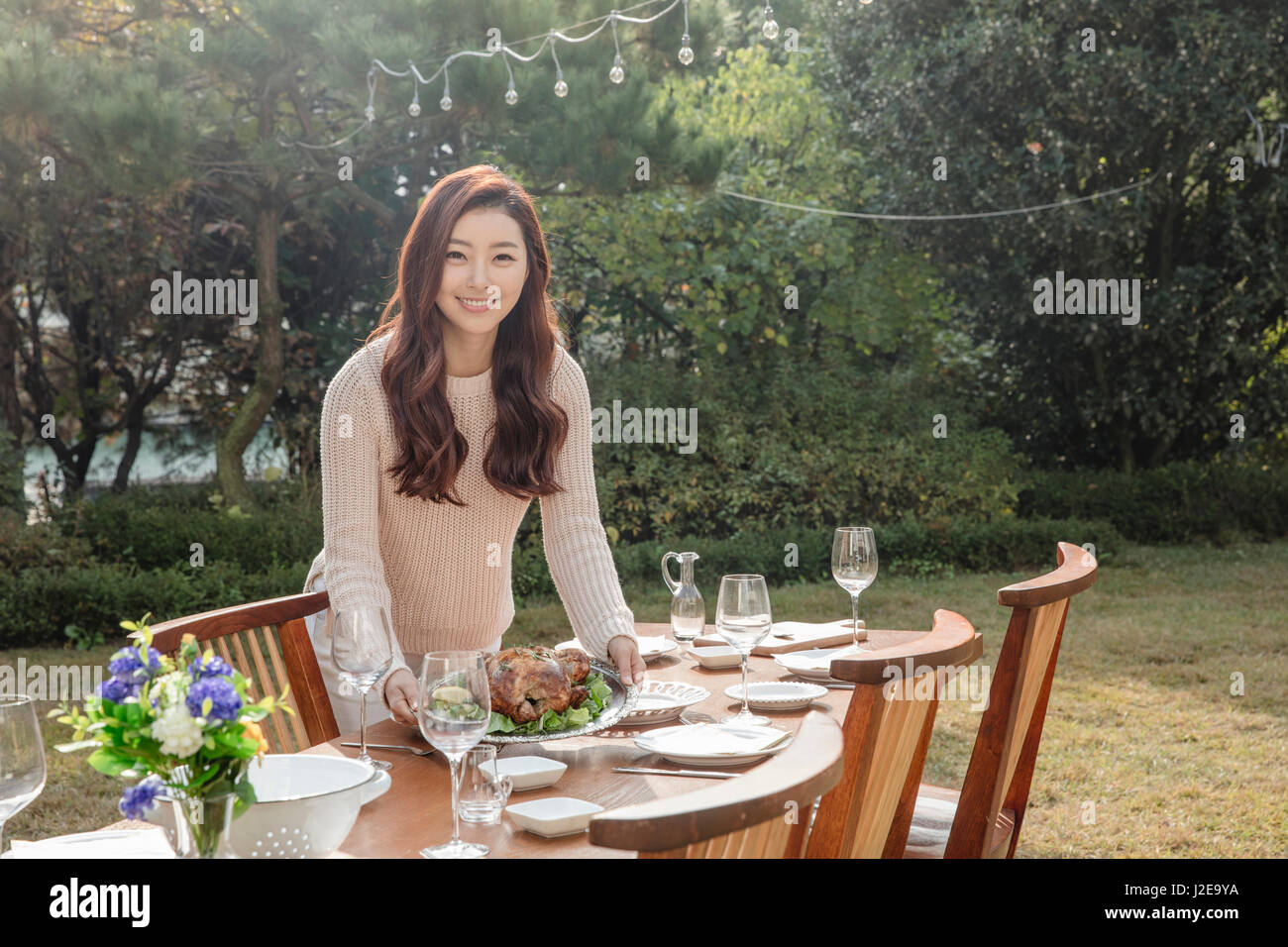 Young smiling woman placing food on table in garden Stock Photo - Alamy