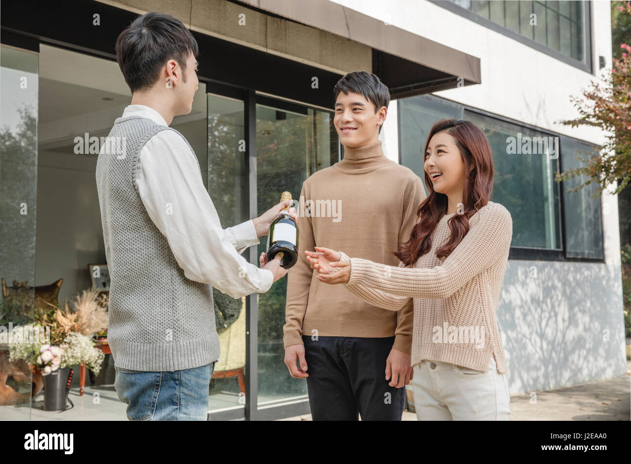 Young people giving and taking wine bottle Stock Photo - Alamy