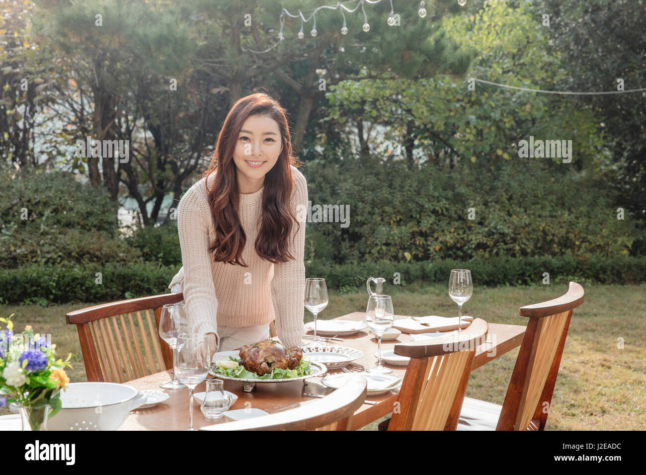 Young smiling woman setting table for party in garden Stock Photo - Alamy