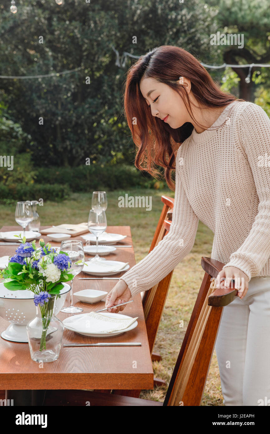 Young smiling woman setting table for garden party Stock Photo - Alamy