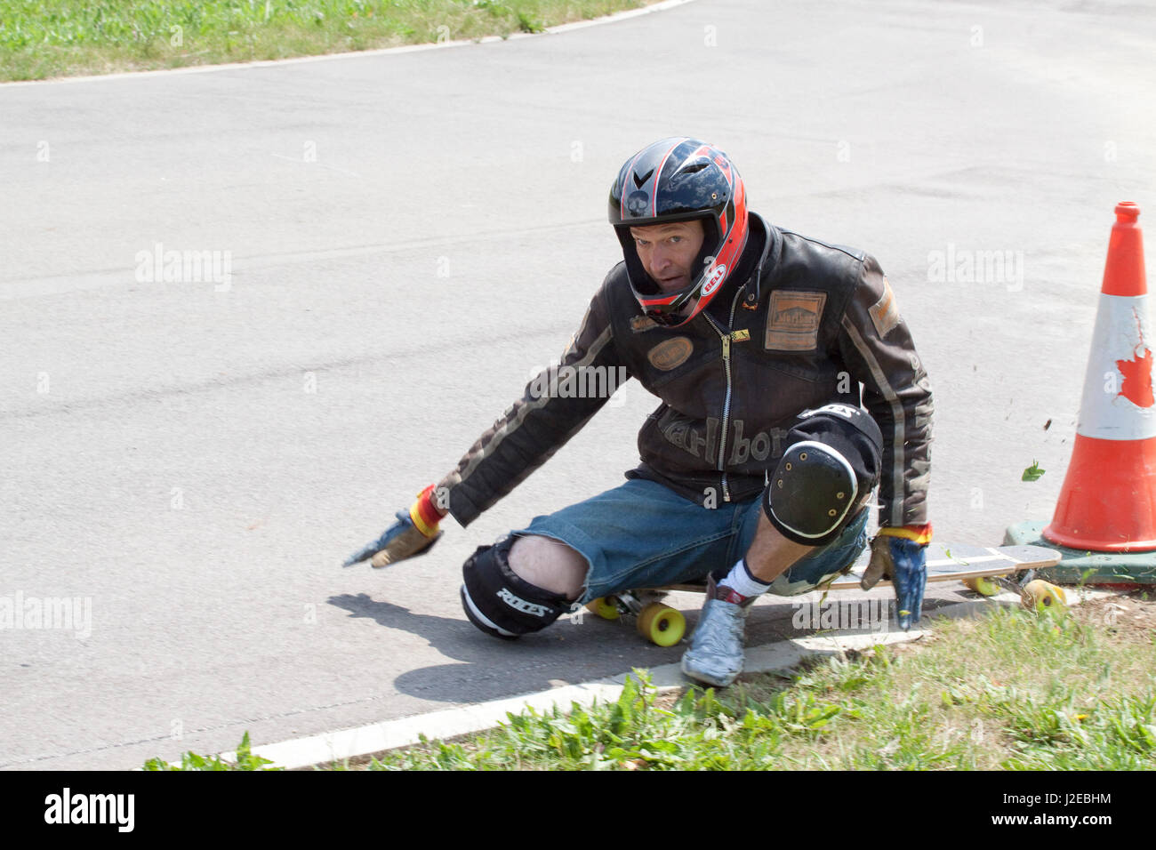 Downhill skateboarder looks at the camera having slid off the road ...