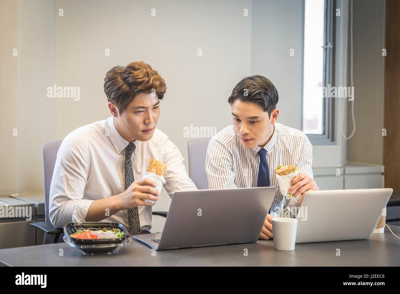 Two businessmen working and eating Stock Photo - Alamy