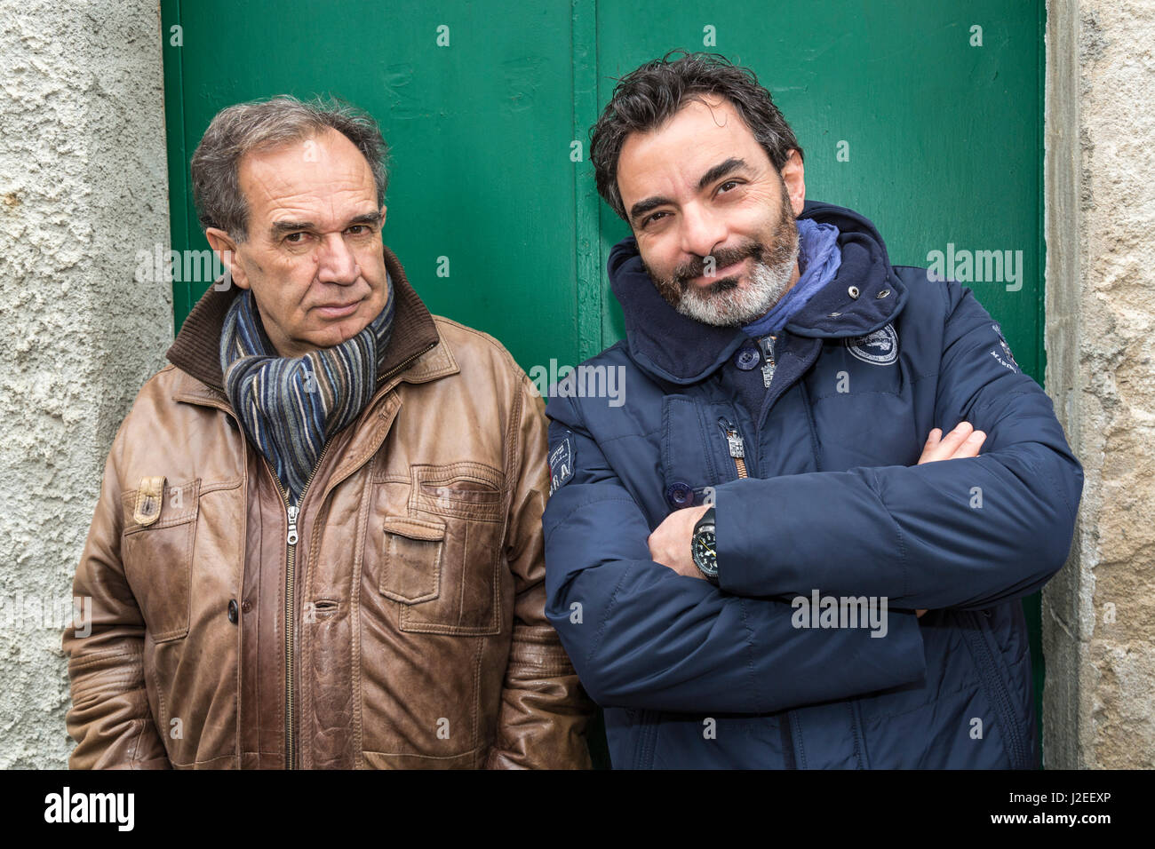 Italy, Sardinia, Mamoiada. Two older men wearing coats looking forward ...