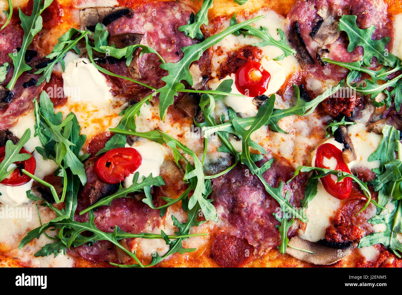 Rocket, chilli peppers, mushroom, salami, harissa and cheese on a pizza ...